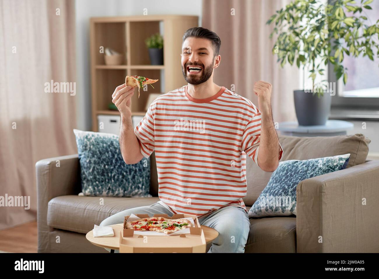 happy man eating takeaway pizza at home Stock Photo - Alamy