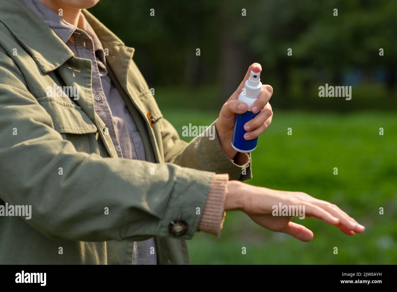 woman spraying insect repellent to hand at park Stock Photo - Alamy