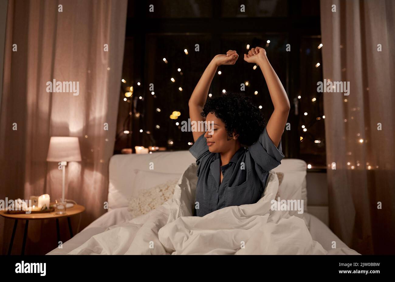 sleepy woman stretching in bed at night Stock Photo - Alamy