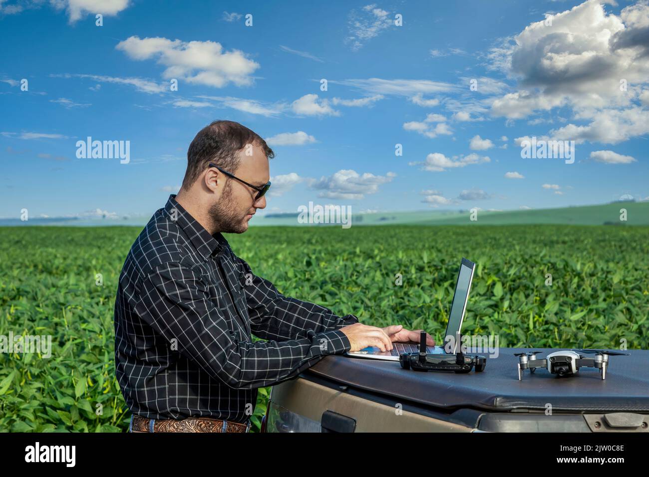 Farmer standing in soybean field looking at notebook and drone Stock ...