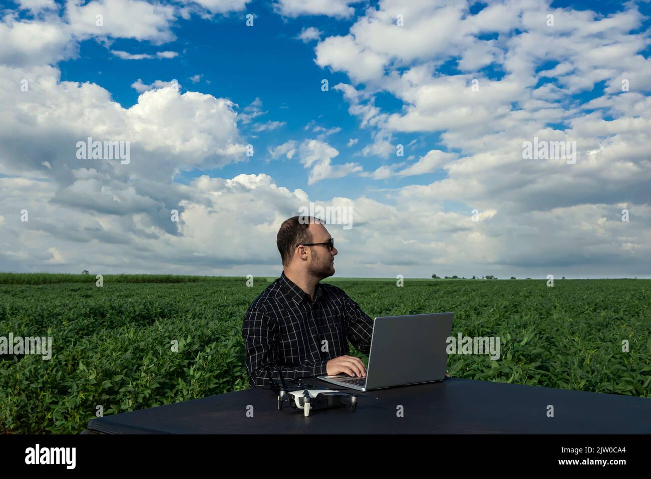 Farmer standing in soybean field looking at notebook and drone Stock ...