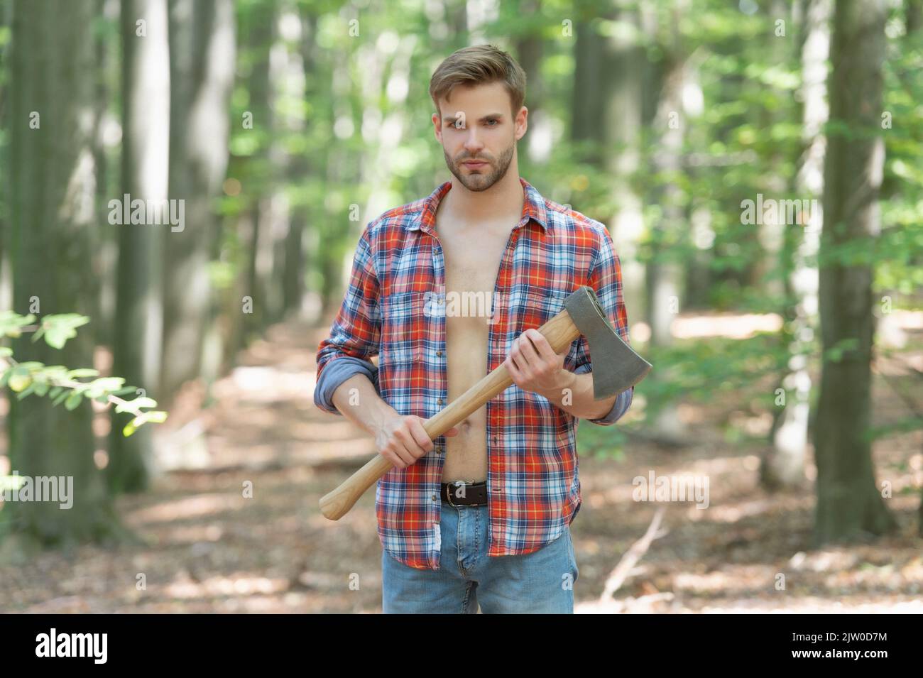 Unshaven axeman man in lumberjack style standing with axe forest ...