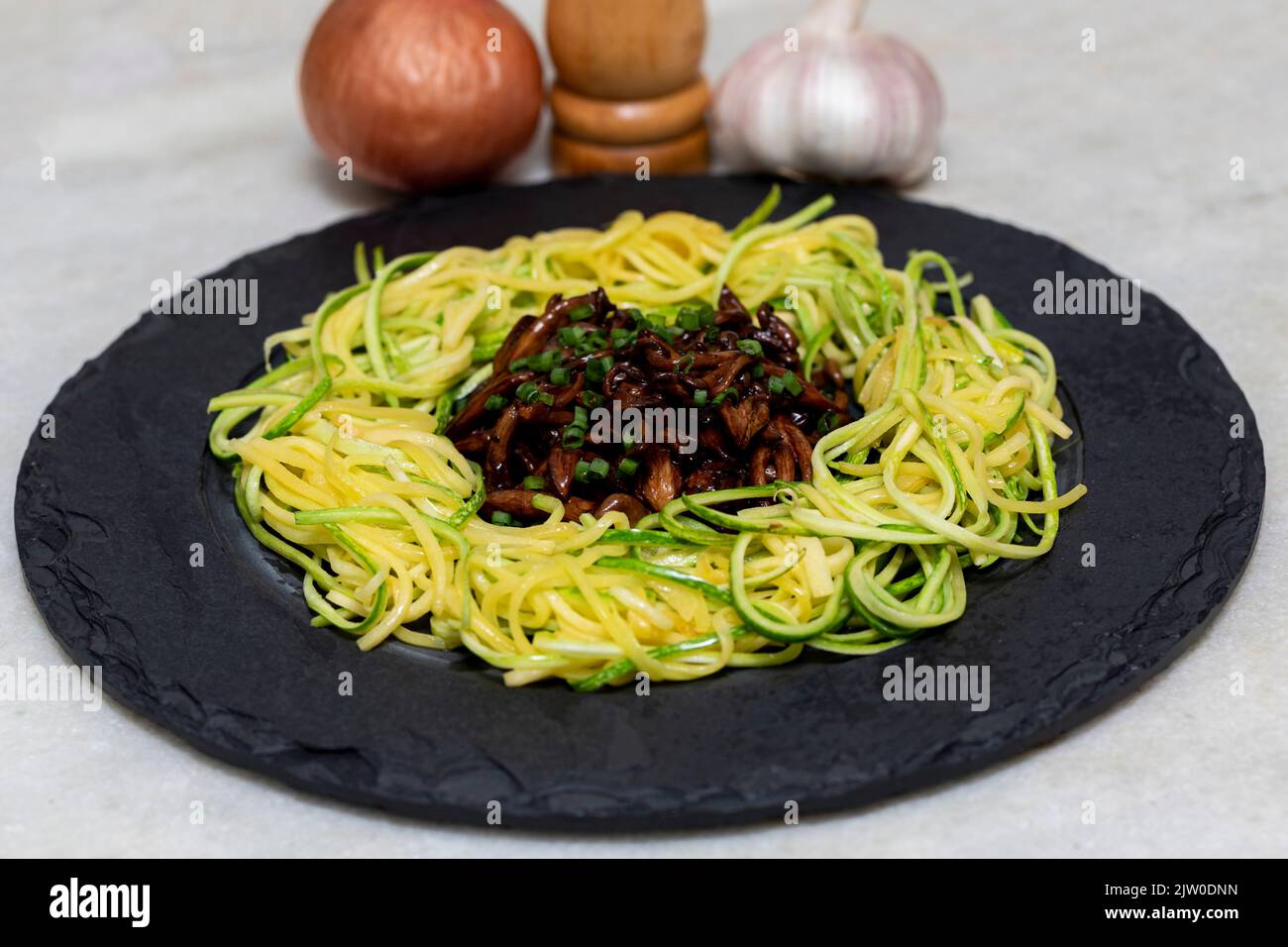 Zucchini spaghetti with shimeji on black stone plate Stock Photo - Alamy