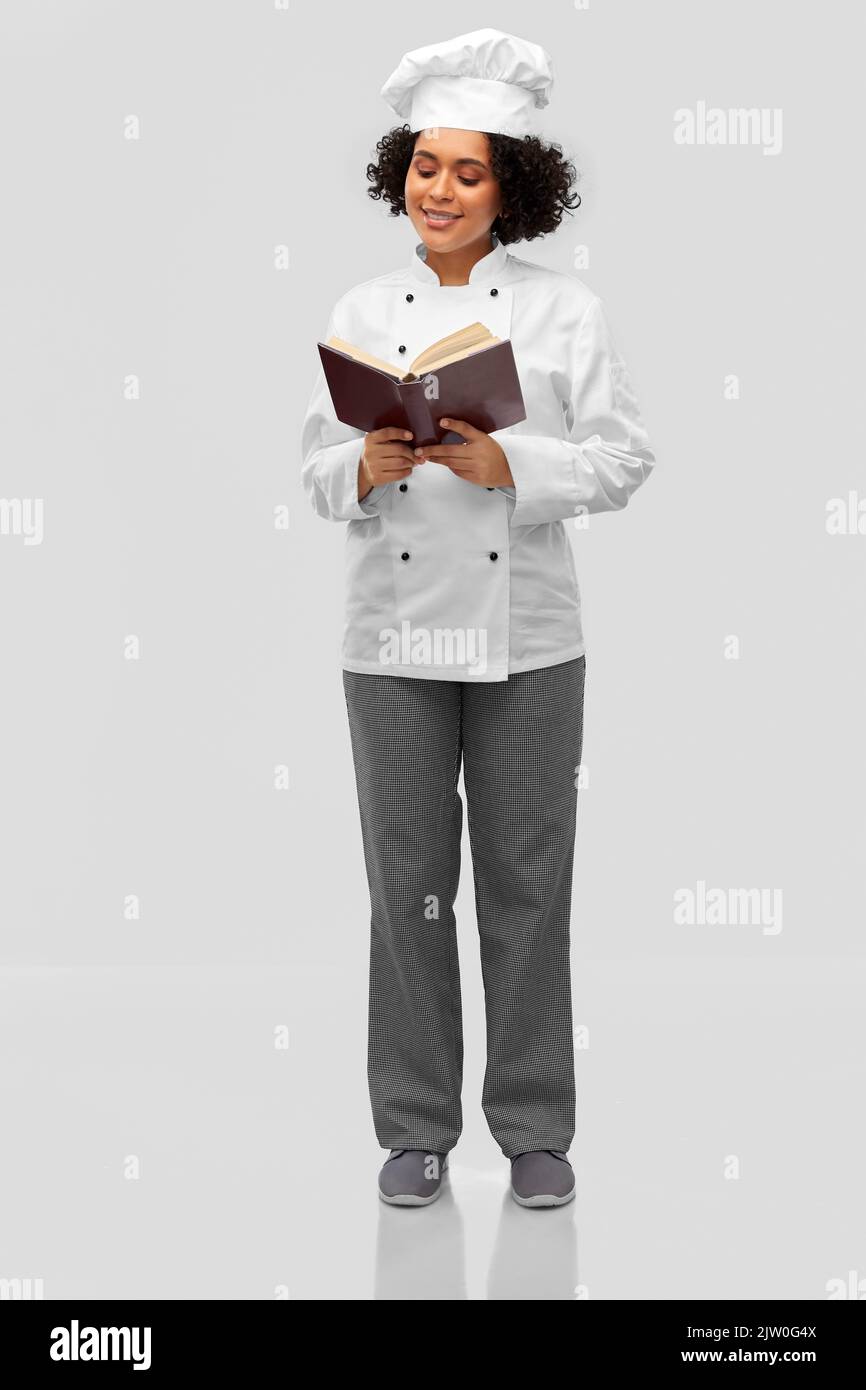 happy female chef in white toque reading cook book Stock Photo - Alamy