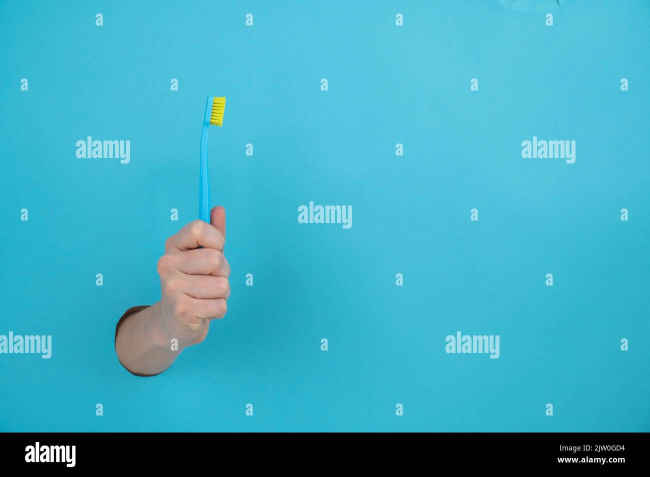 A woman's hand sticks out of a blue paper background and holds a ...
