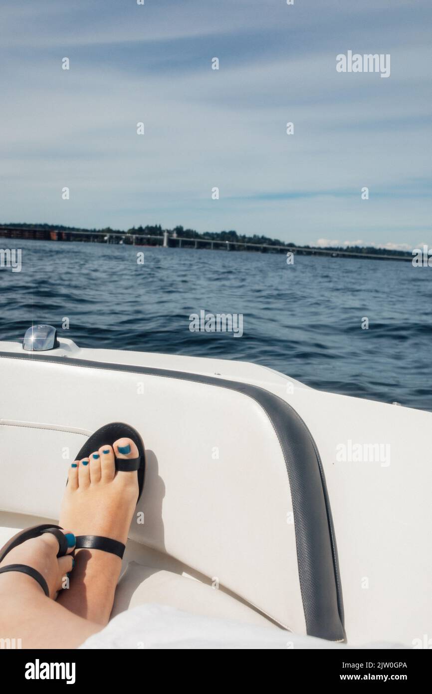 feet with blue toenails and black toe sandals resting on bow of boat in ...