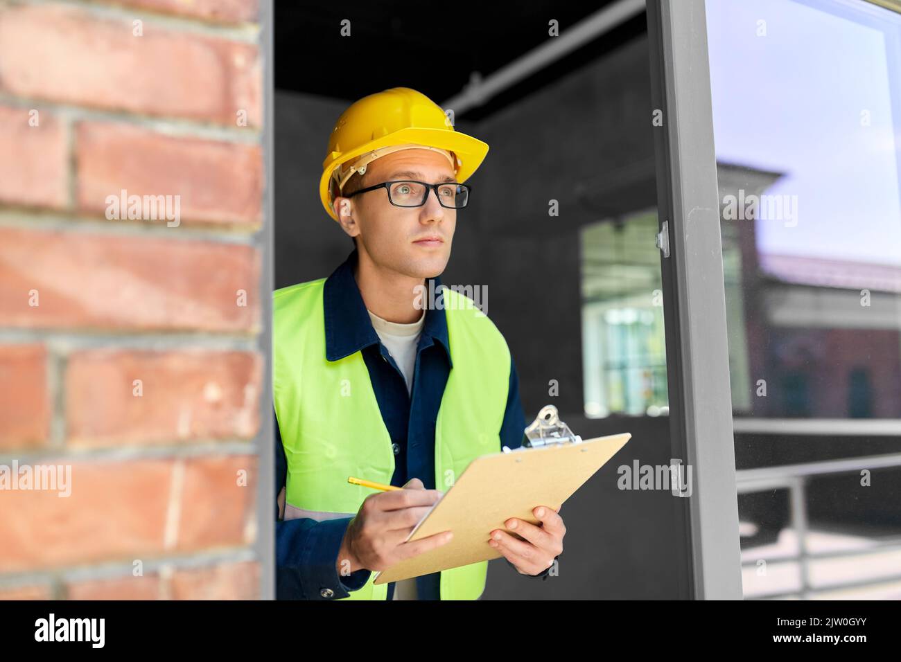 male builder with clipboard looking out window Stock Photo - Alamy