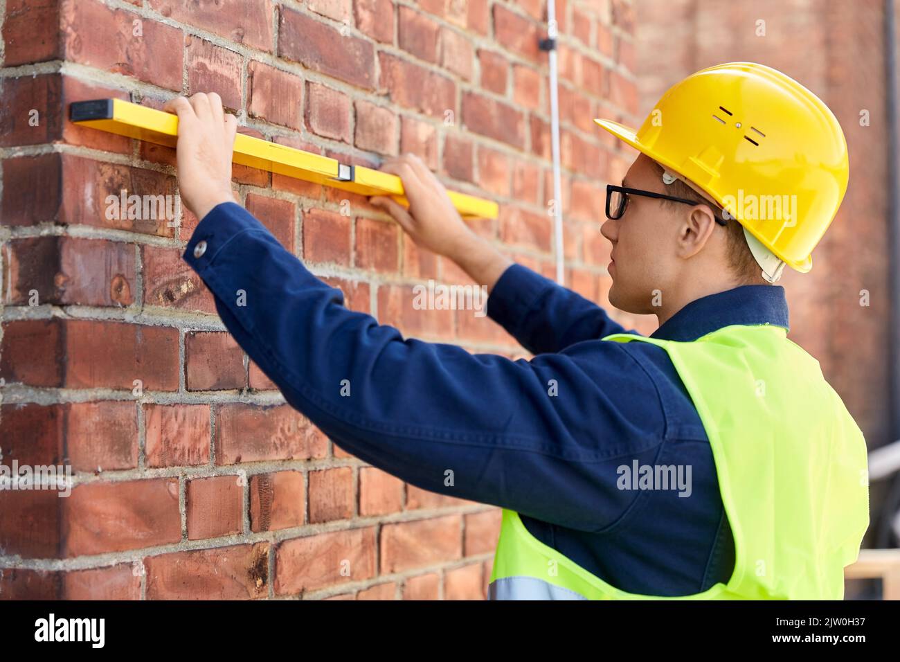 male builder with level measuring wall Stock Photo - Alamy