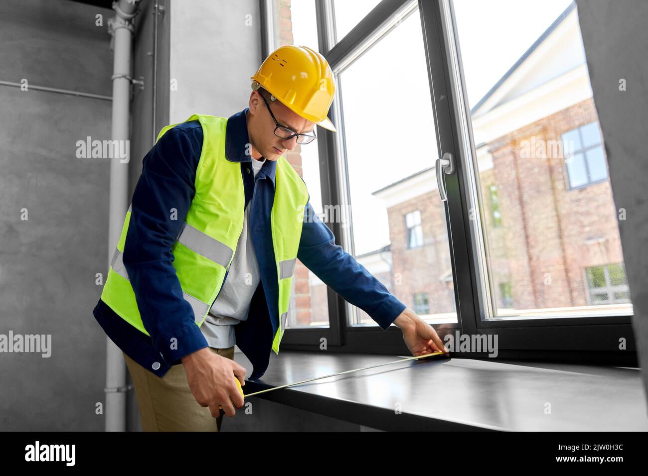 male builder with ruler measuring window sill Stock Photo - Alamy
