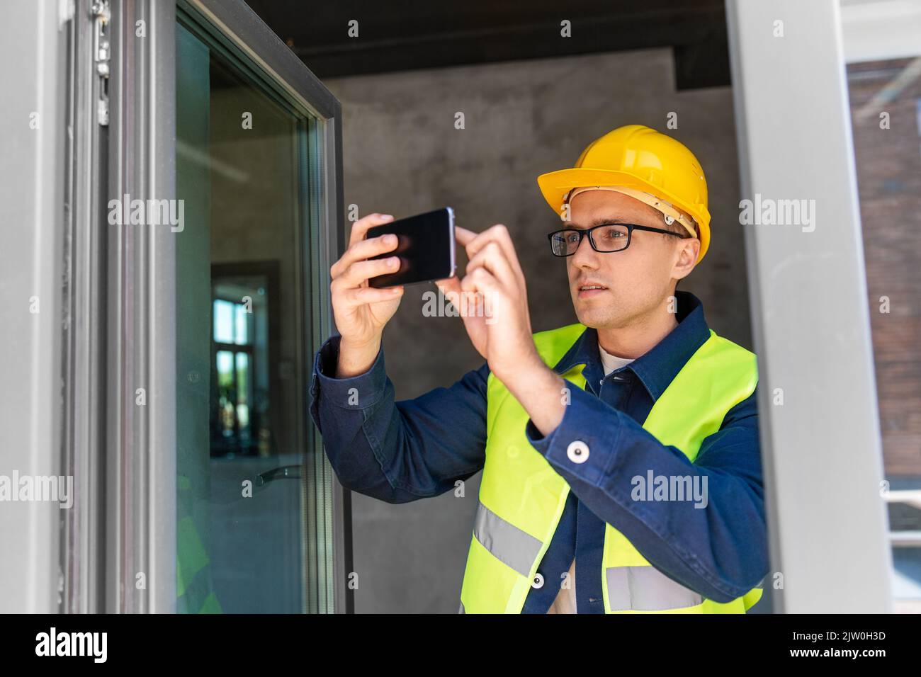 builder with smartphone taking picture at window Stock Photo - Alamy