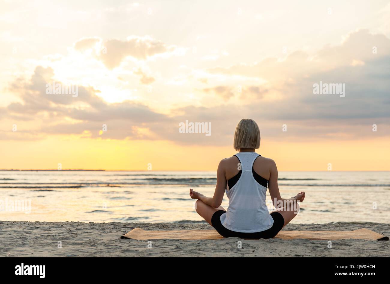 woman meditating in lotus pose on beach Stock Photo - Alamy