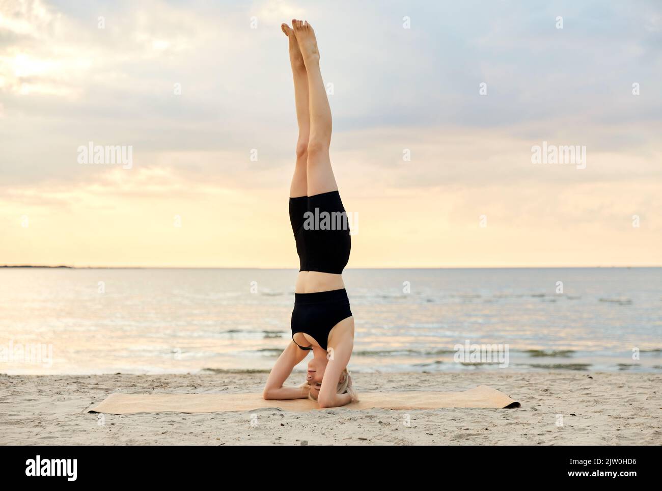 woman doing yoga headstand on beach Stock Photo - Alamy