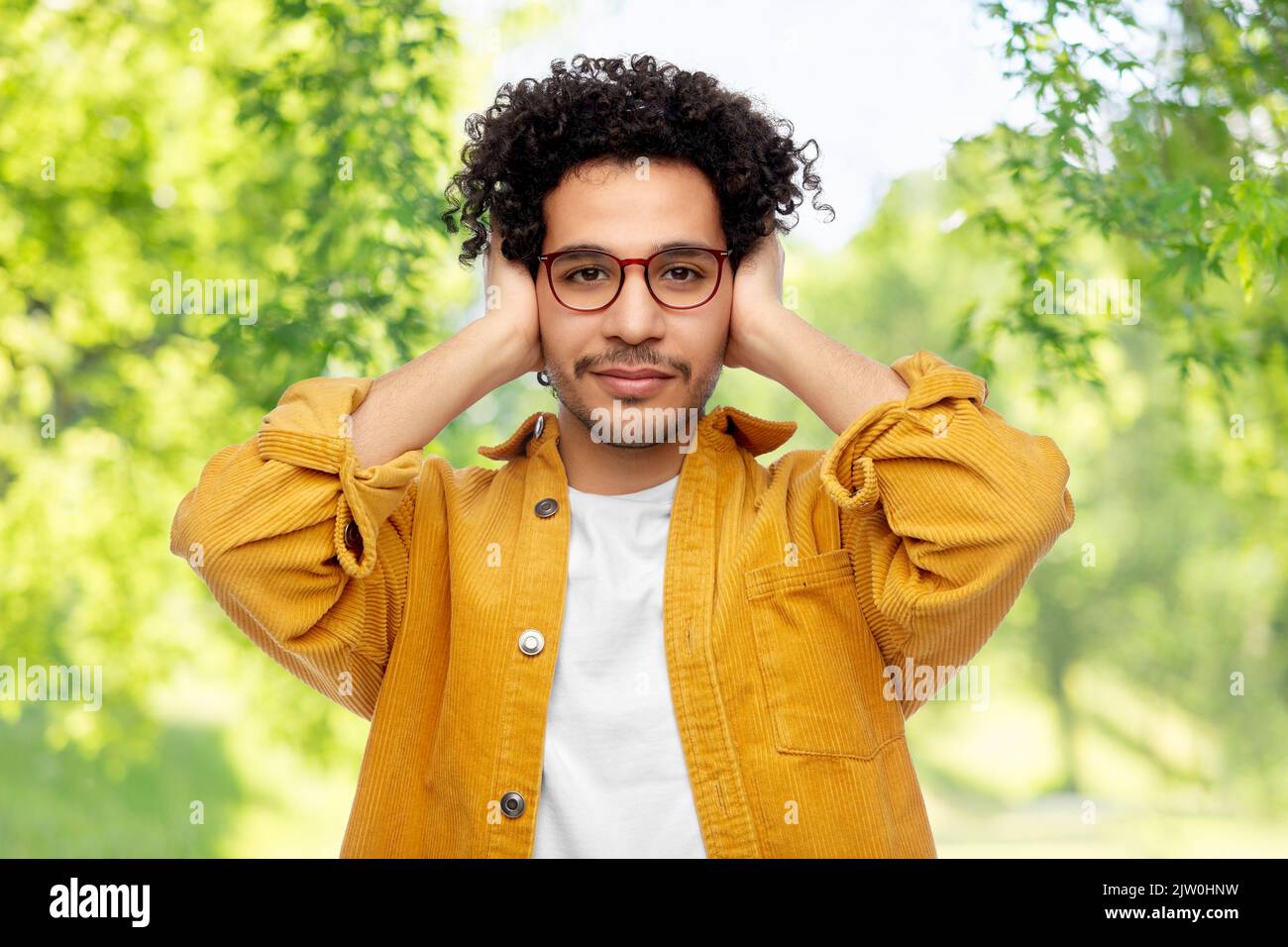 man closing ears by hands on natural background Stock Photo - Alamy