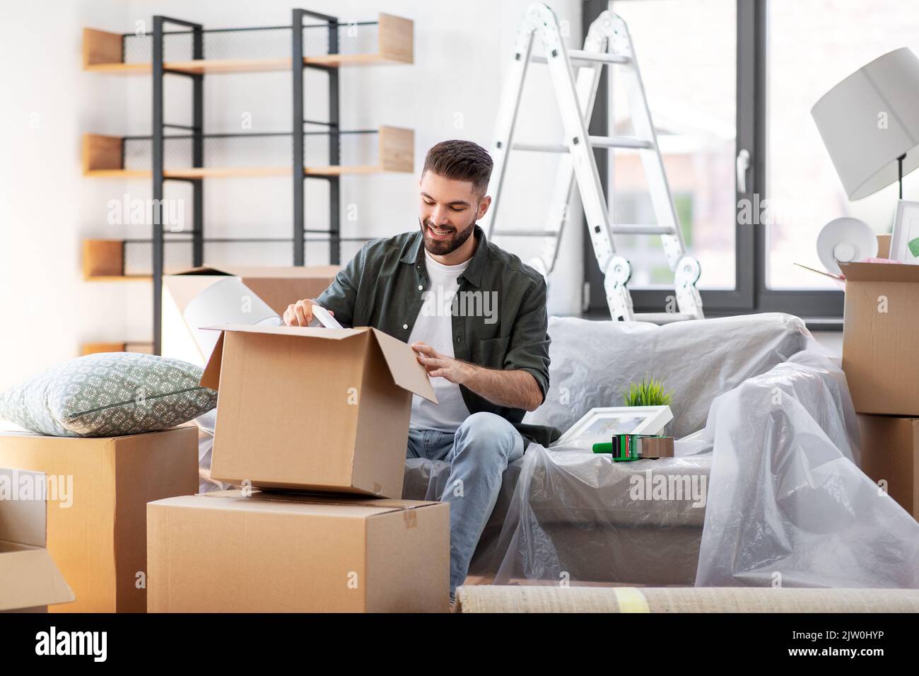 happy man unpacking boxes and moving to new home Stock Photo - Alamy
