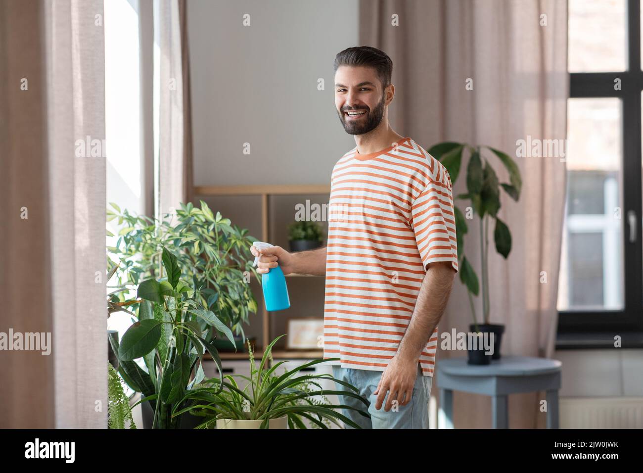 Happy man spraying houseplant water hi-res stock photography and images ...
