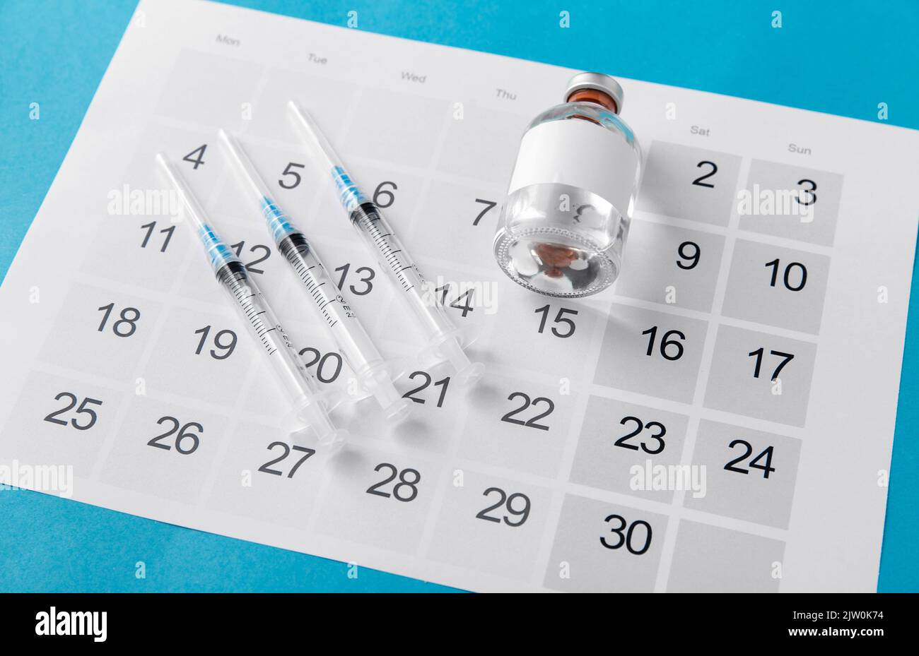 disposable syringe and calendar on blue background Stock Photo - Alamy