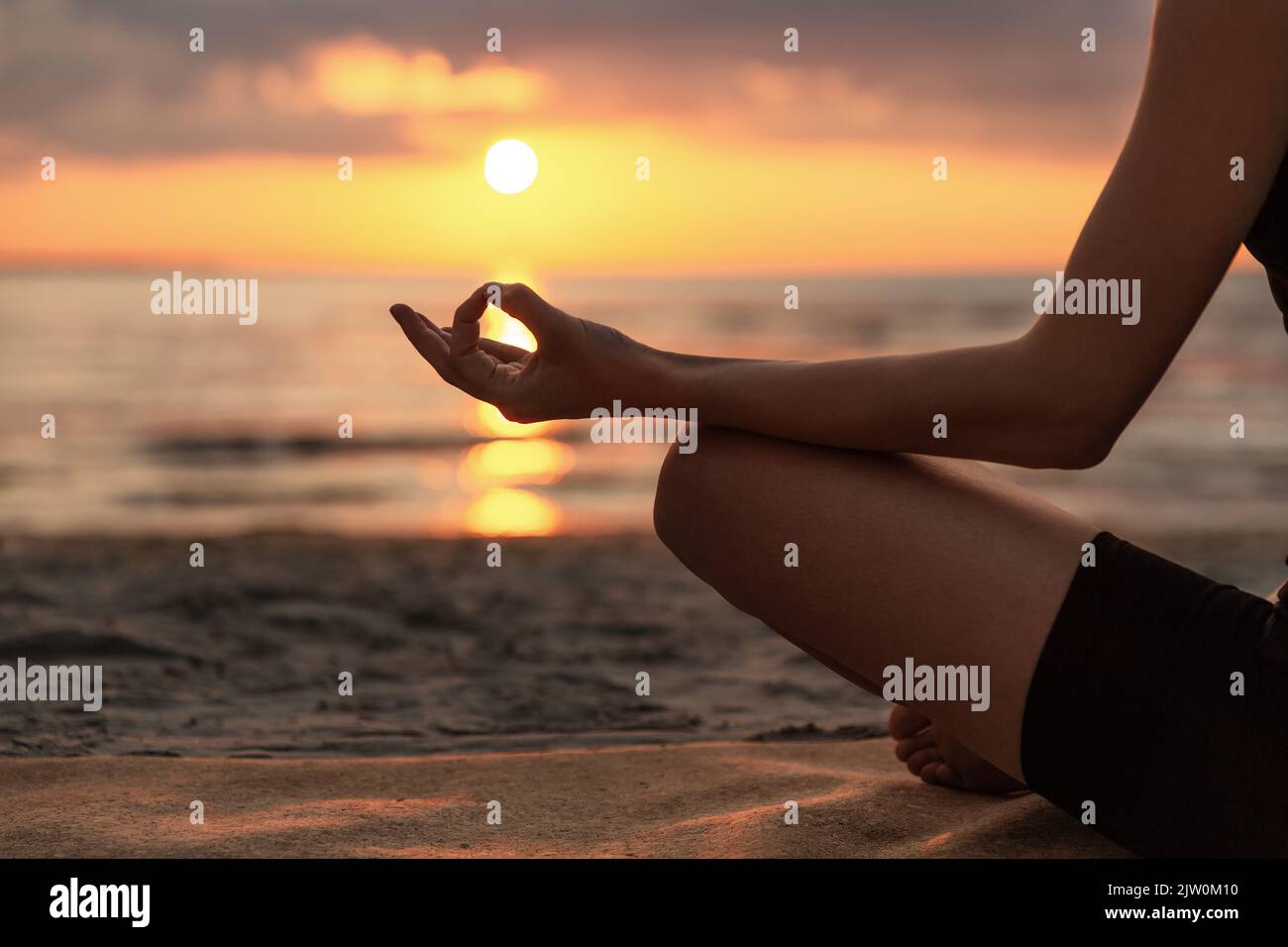 woman meditating in lotus pose on beach Stock Photo - Alamy