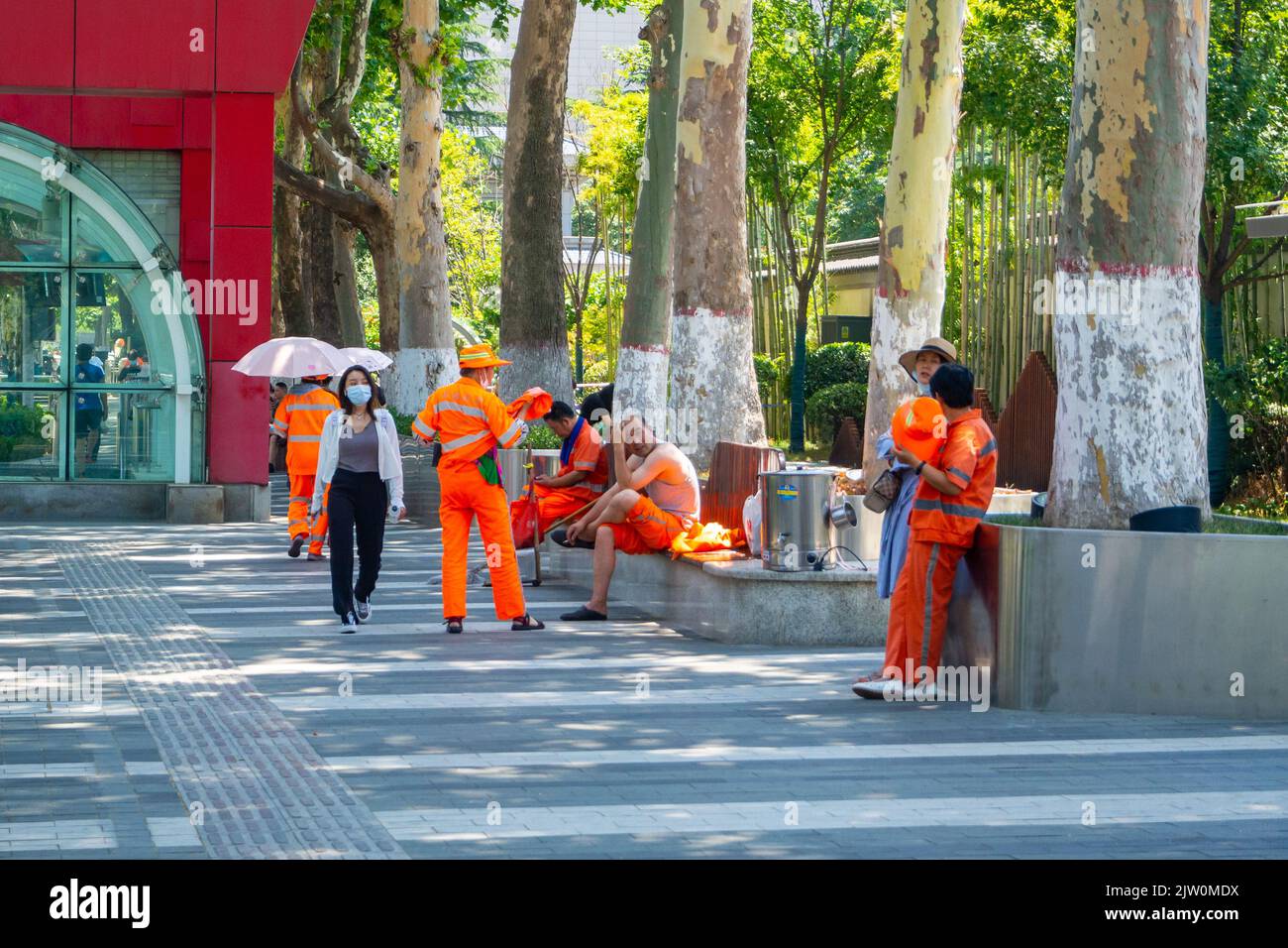 Chinese people in street sweeper uniforms. They are taking a break ...