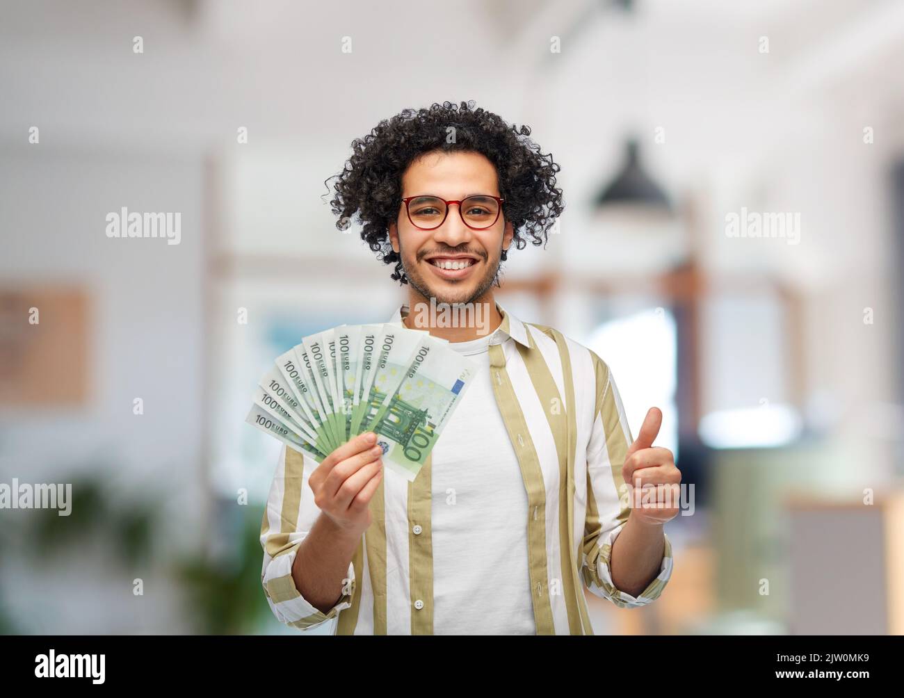 happy man with money showing thumbs up at office Stock Photo - Alamy