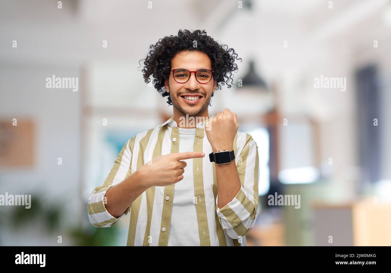 happy man in glasses showing smart watch at office Stock Photo - Alamy