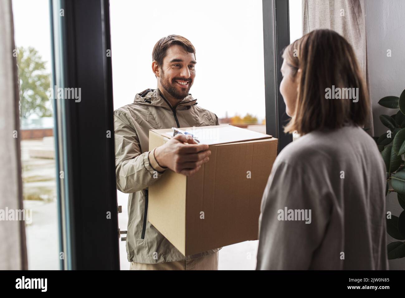 delivery man with parcel box and customer at home Stock Photo - Alamy
