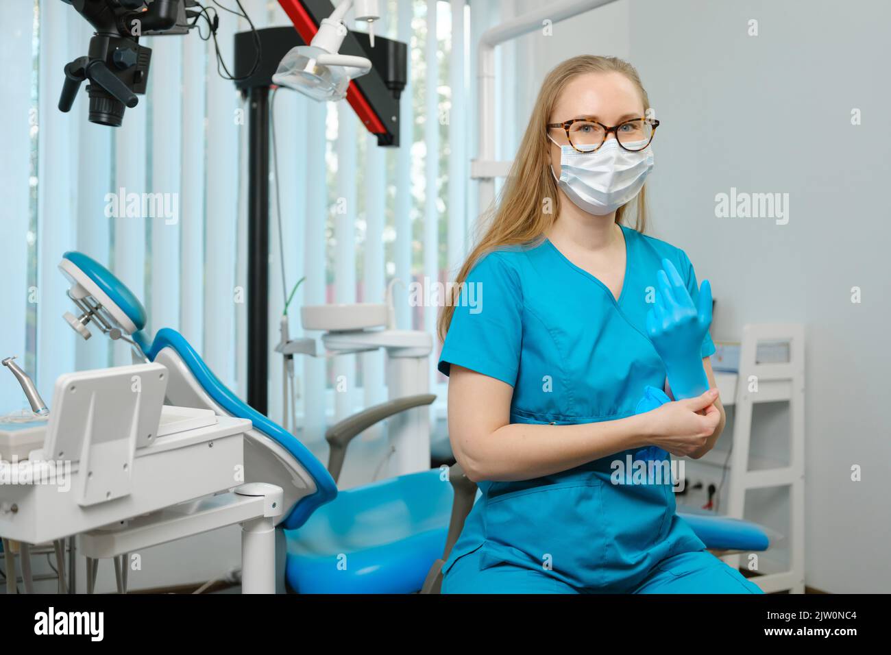 Happy caucasian female dentist in blue lab coat and protective facial ...