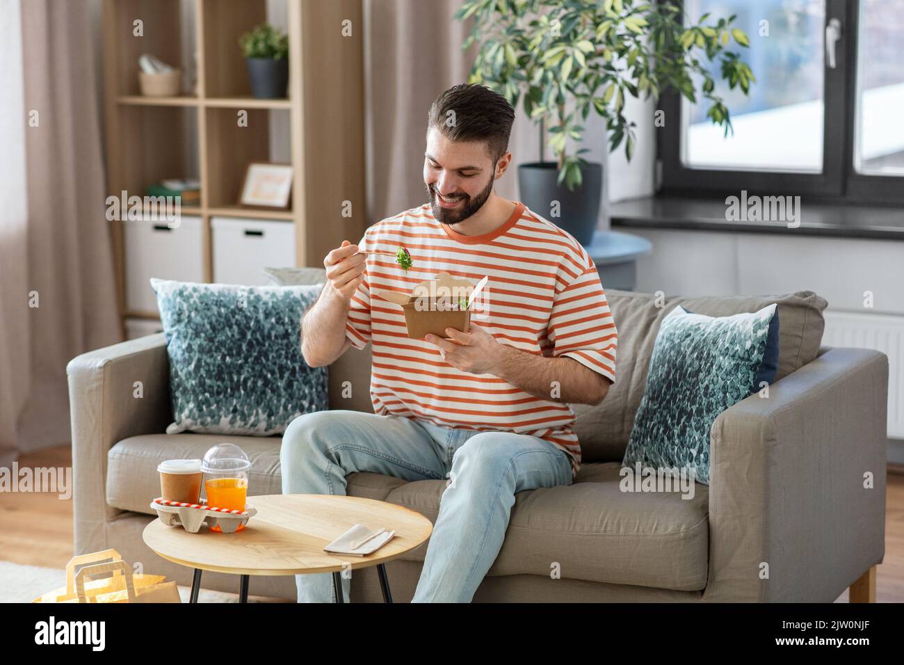 smiling man eating takeaway food at home Stock Photo - Alamy