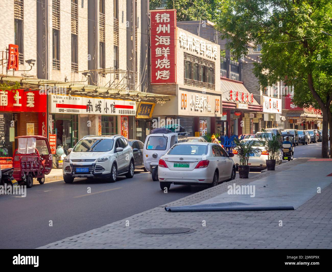 The traffic of cars and other vehicles in a business area. Facades of ...