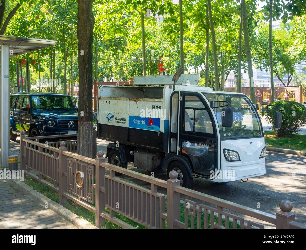 Small garbage truck parked in a city street. The area has beautiful ...