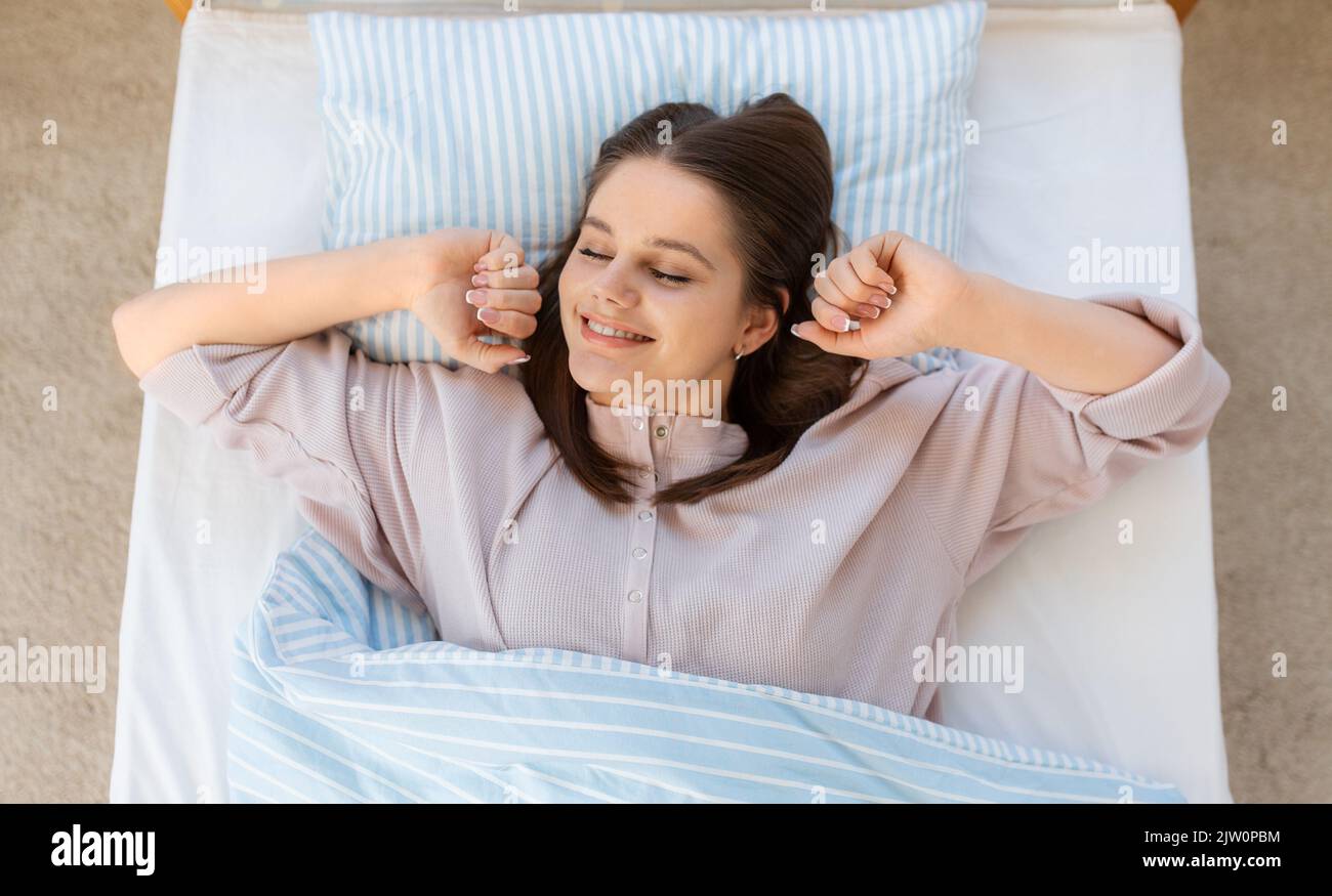 happy smiling girl stretching in bed Stock Photo - Alamy