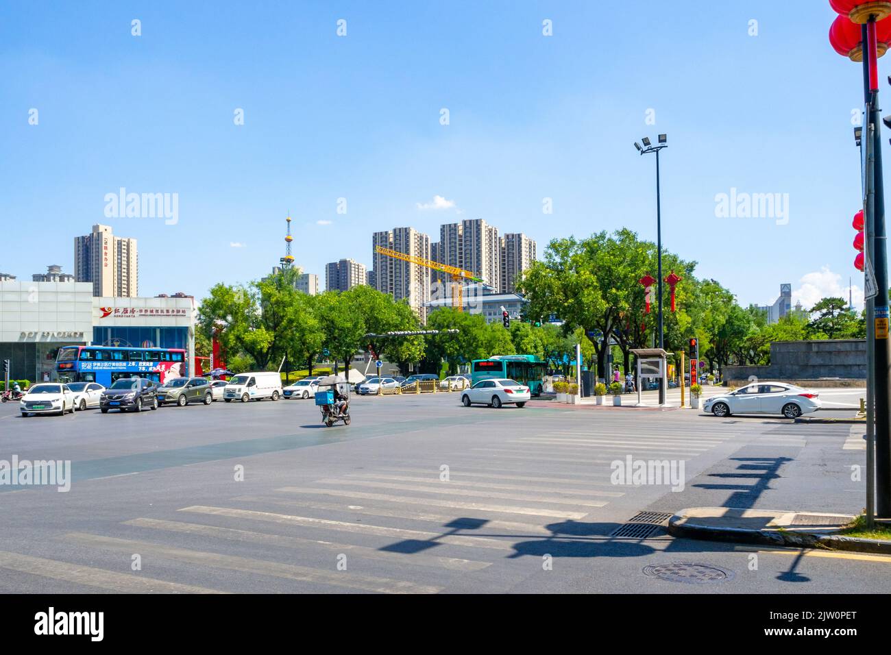 A city crosswalk in a wide downtown avenue. The cityscape shows modern ...