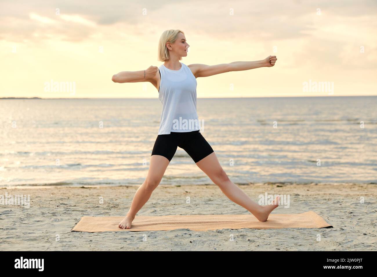 woman doing yoga archer pose on beach Stock Photo - Alamy