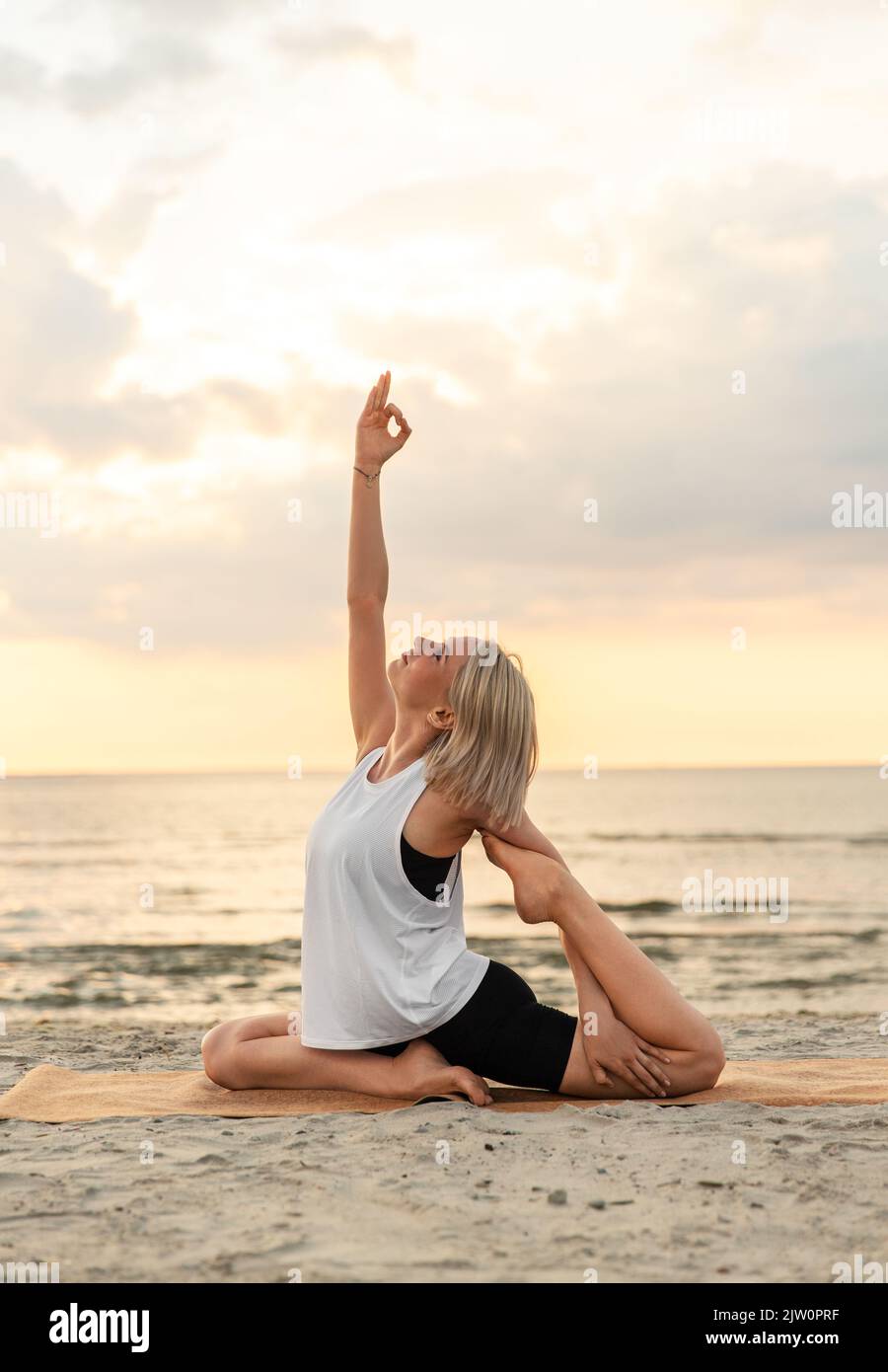 woman doing yoga mermaid pose on beach Stock Photo - Alamy