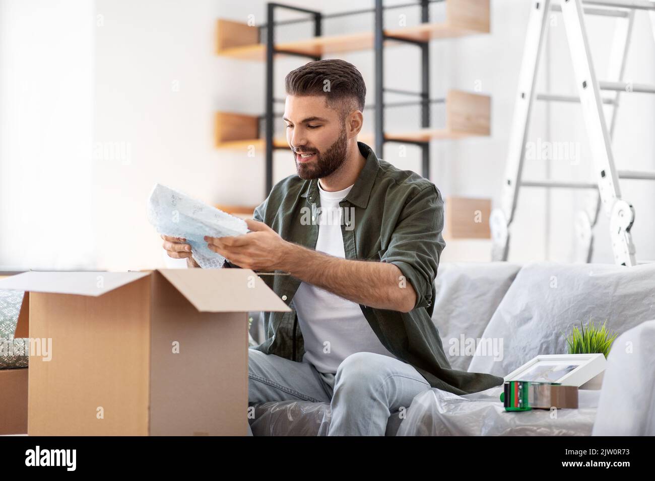 happy man unpacking boxes and moving to new home Stock Photo - Alamy