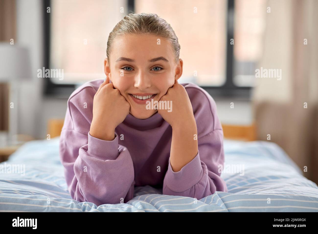 happy smiling girl lying on bed at home Stock Photo - Alamy