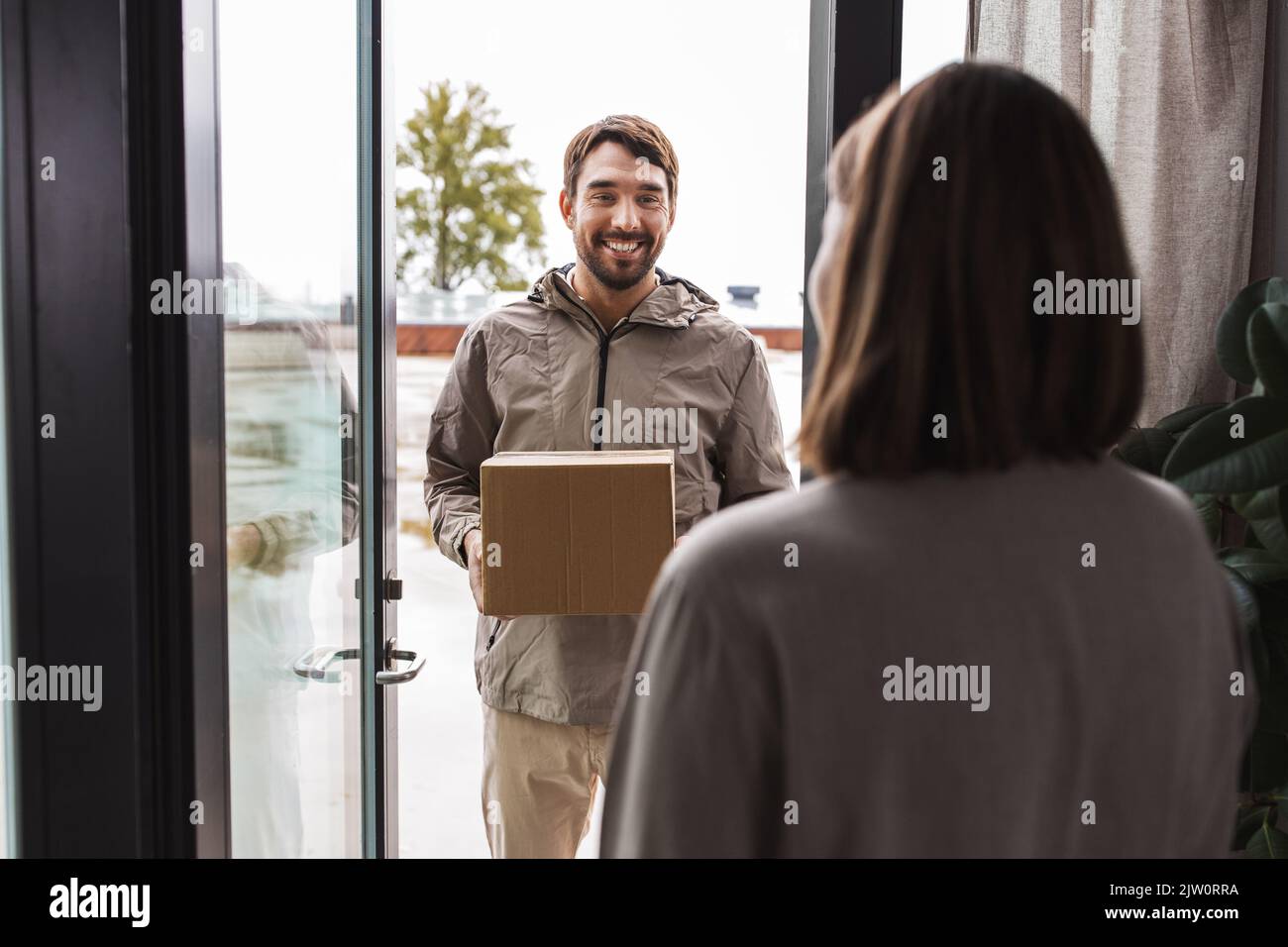 delivery man with parcel box and customer at home Stock Photo - Alamy