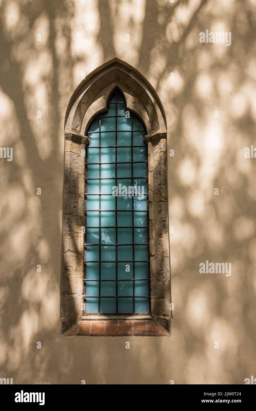 A gothic style church window with iron bars with a green curtain and a ...