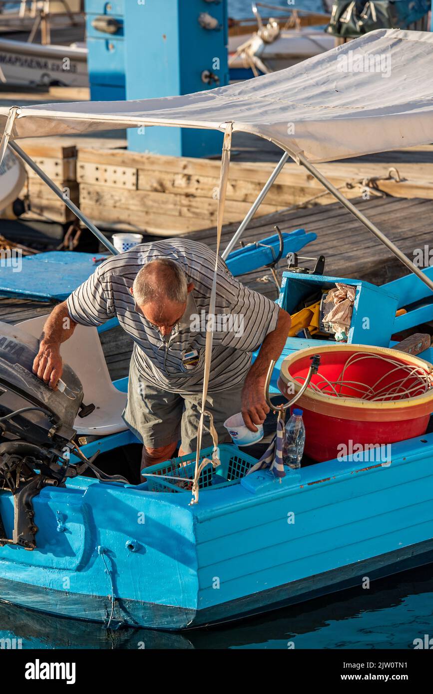 greek fisherman working on boat in harbour at chania on crete ...