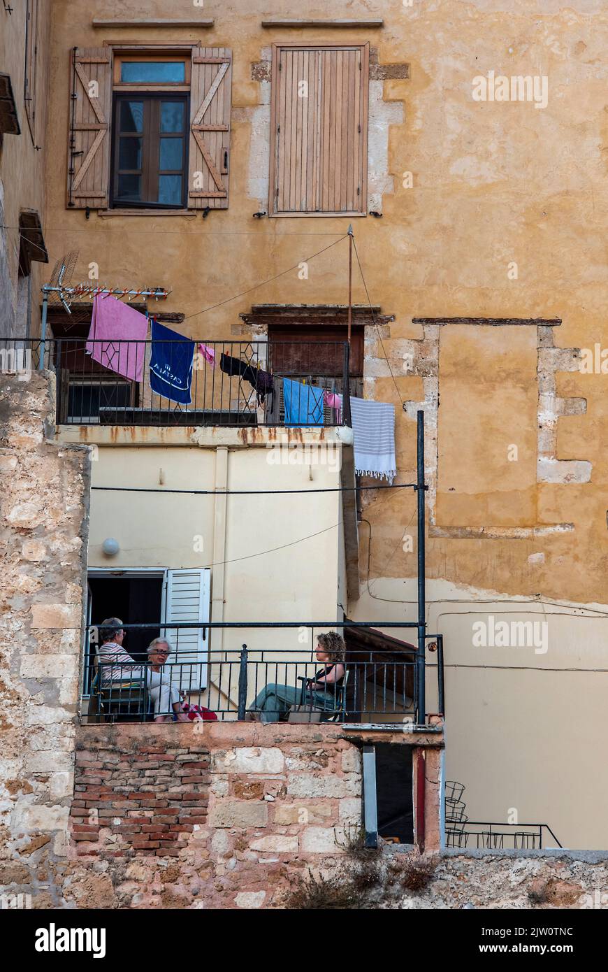 older greek friends and families sitting on a balcony on a block of ...
