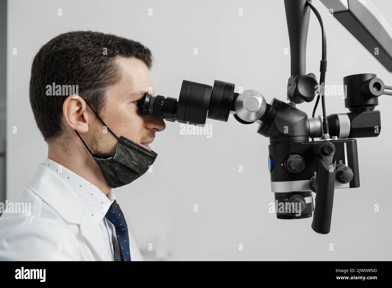 Male dentist using dental microscope treating female patient teeth at ...