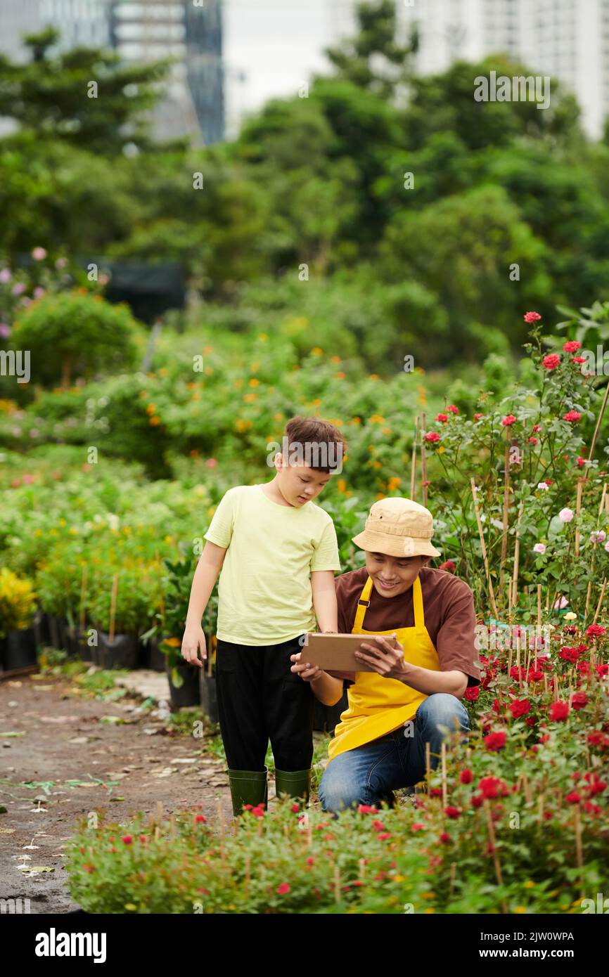 Father and son counting plants in flower nursery and filling form on ...