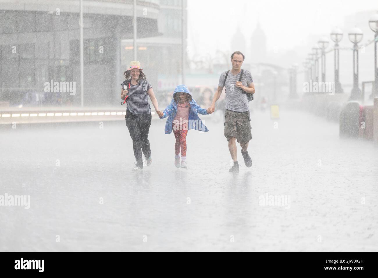 Amber rain catches Londoners this afternoon at Tower Bridge. Image shot ...