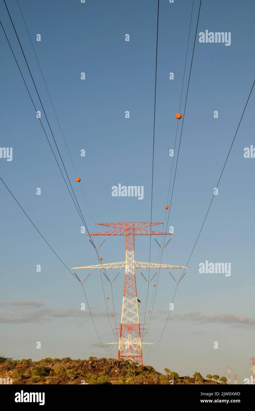 A vertical low angle shot of an electricity power pylon with cables on ...