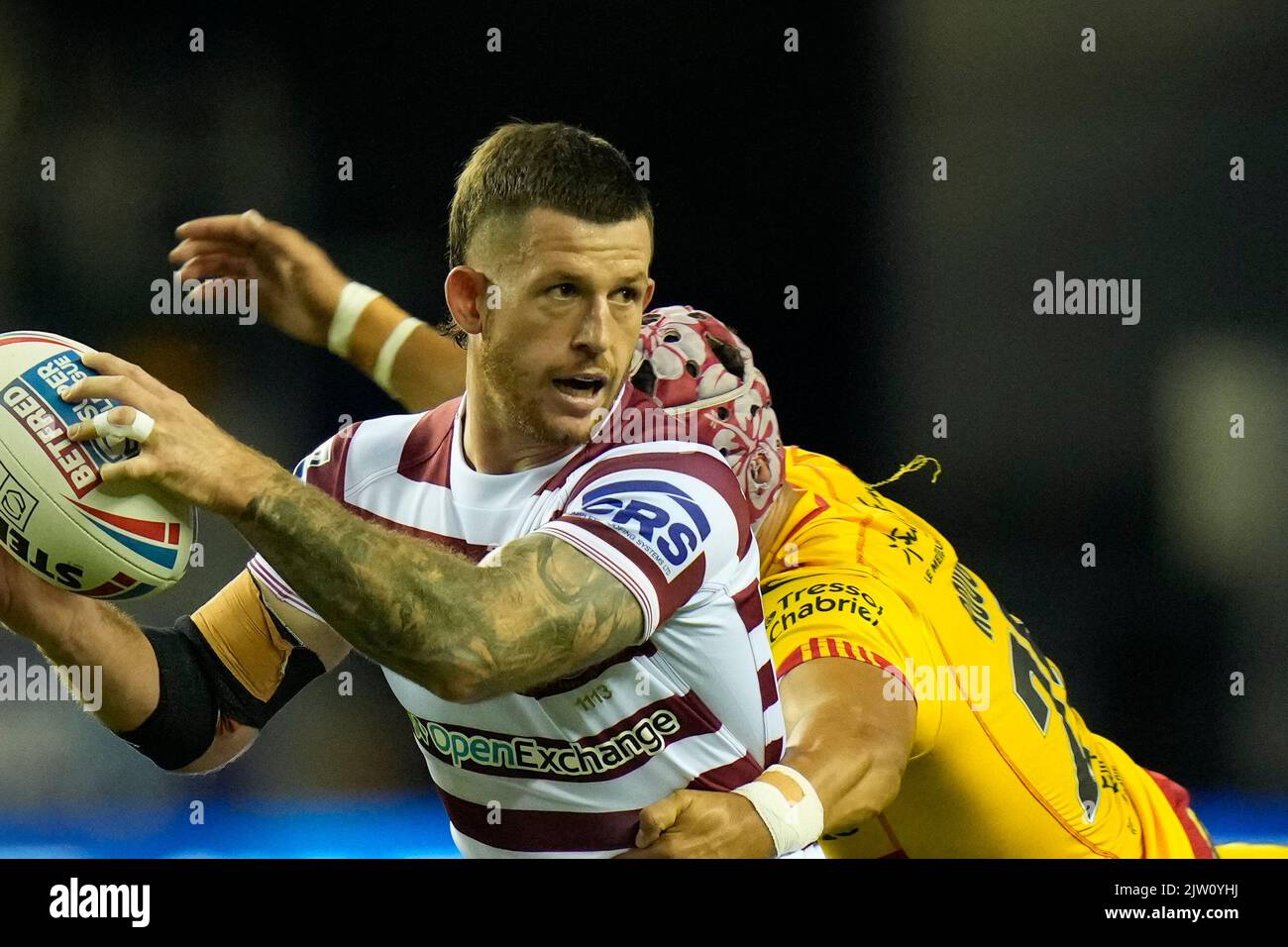 Cade Cust #6 of Wigan Warriors tackles by Cesar Rouge #25 of Catalans ...