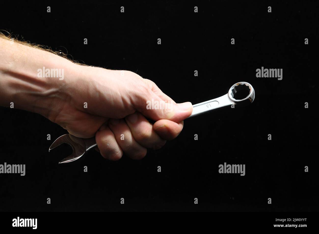 A male hand holding a key bolt Capri tool in front of a black ...