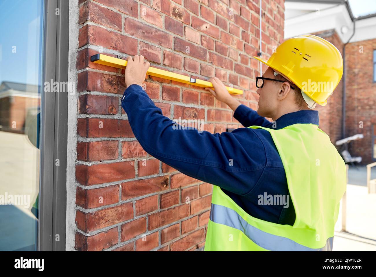 male builder with level measuring wall Stock Photo - Alamy