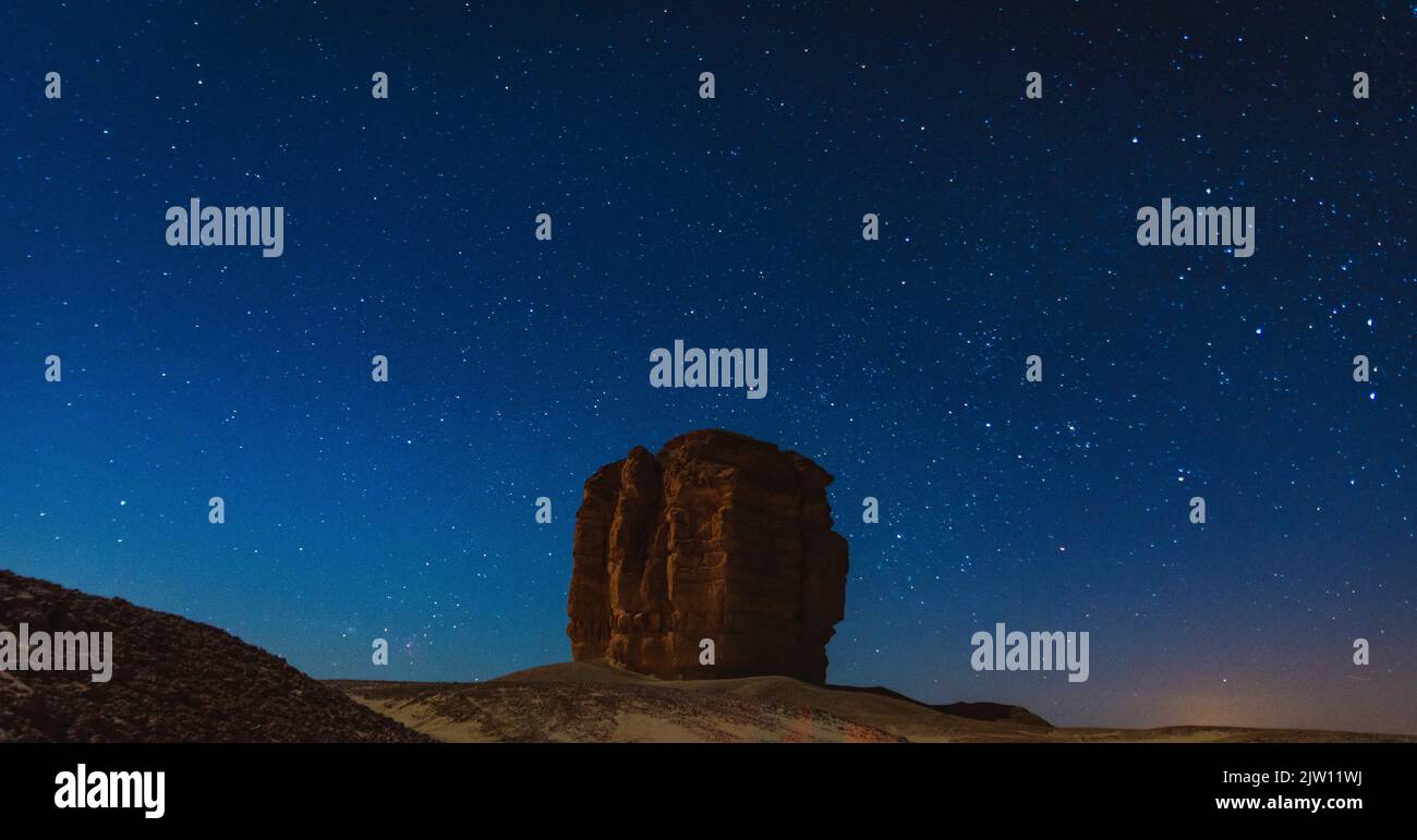 A sandstone structure in the desert at night with stars in background ...