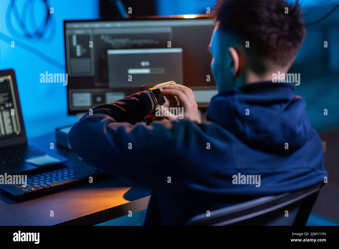 hacker with smart watch and computers in dark room Stock Photo - Alamy