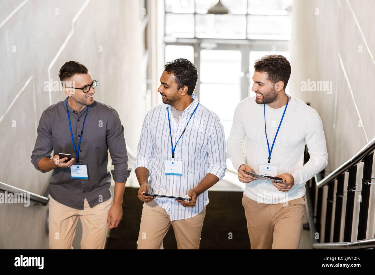 men with conference badges walking upstairs Stock Photo - Alamy