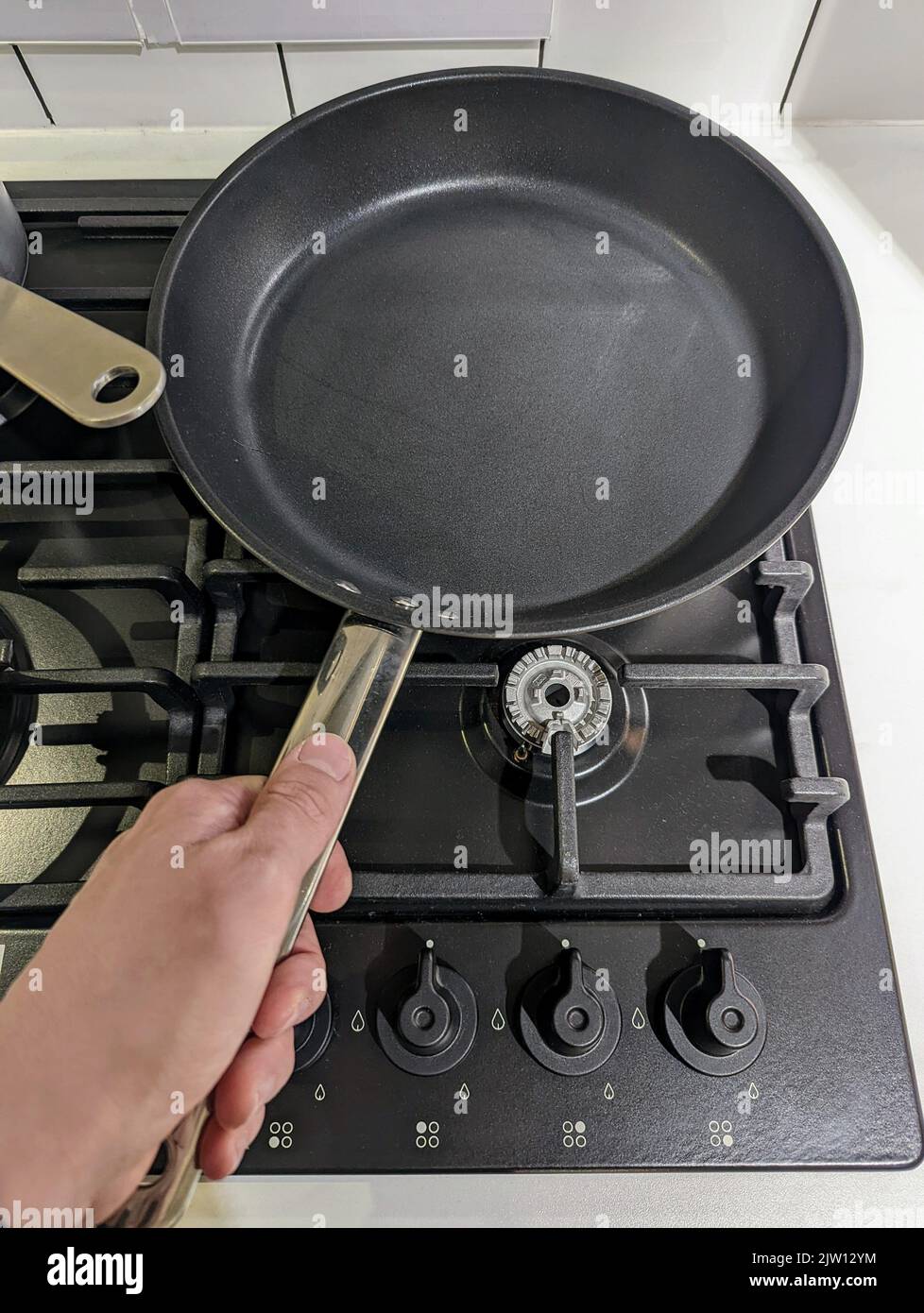 A vertical top view of human hand holding an empty pan putting it on ...